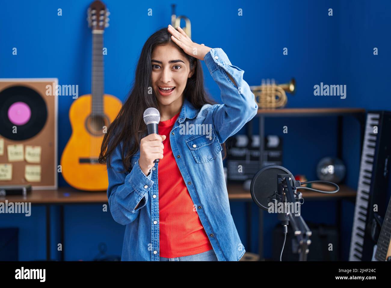 Young teenager girl singing song using microphone stressed and ...