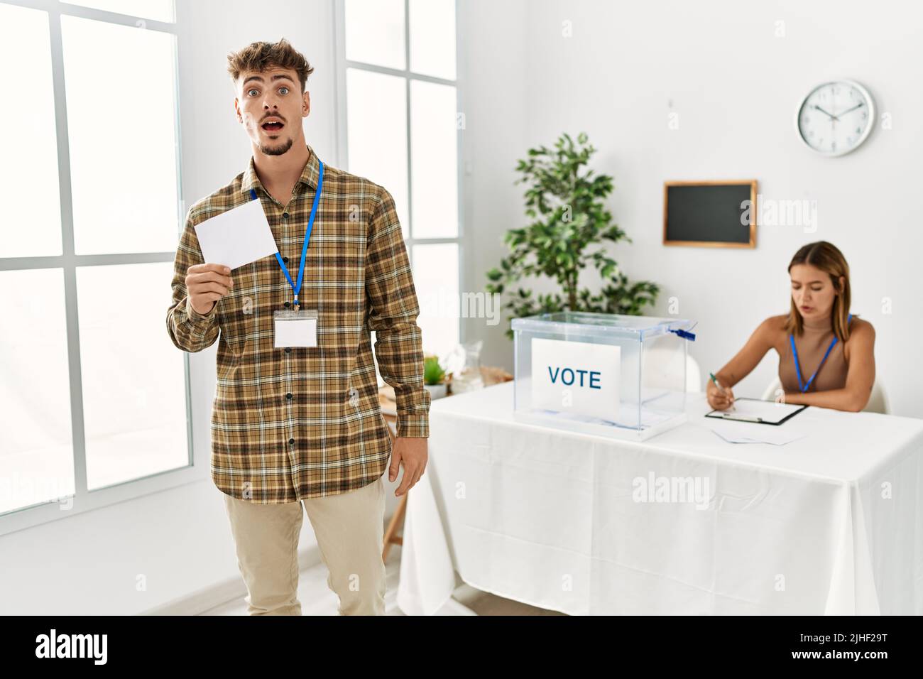 Young handsome man voting putting envelop in ballot box scared and ...