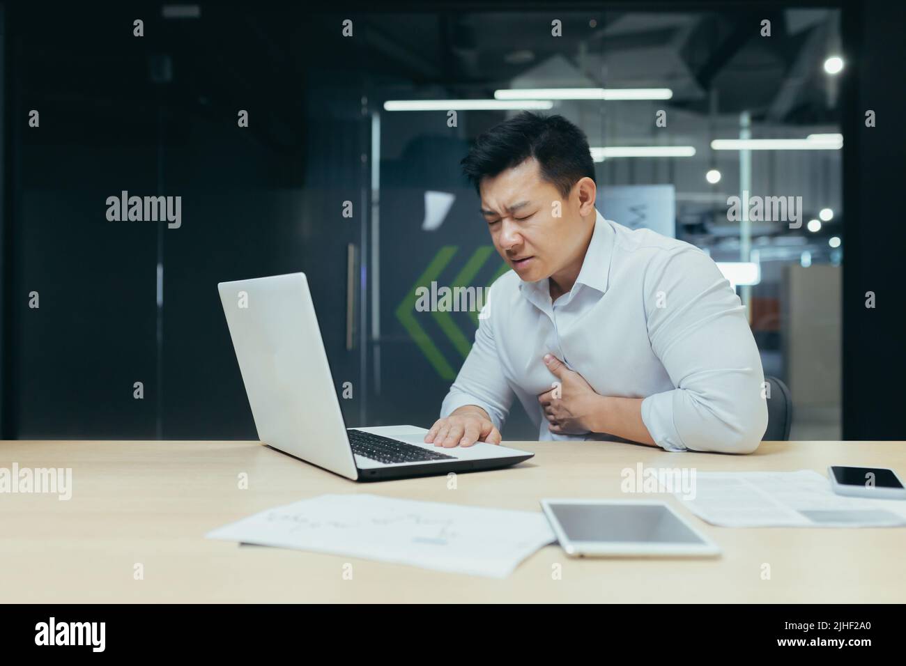 Sick Asian businessman at work, man chest pain heart, overworked and ...