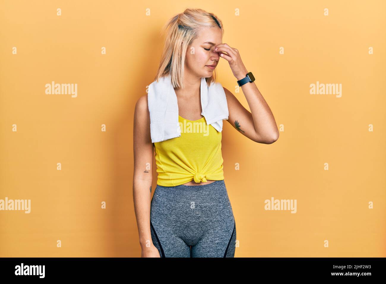 Beautiful blonde sports woman wearing workout outfit tired rubbing nose ...