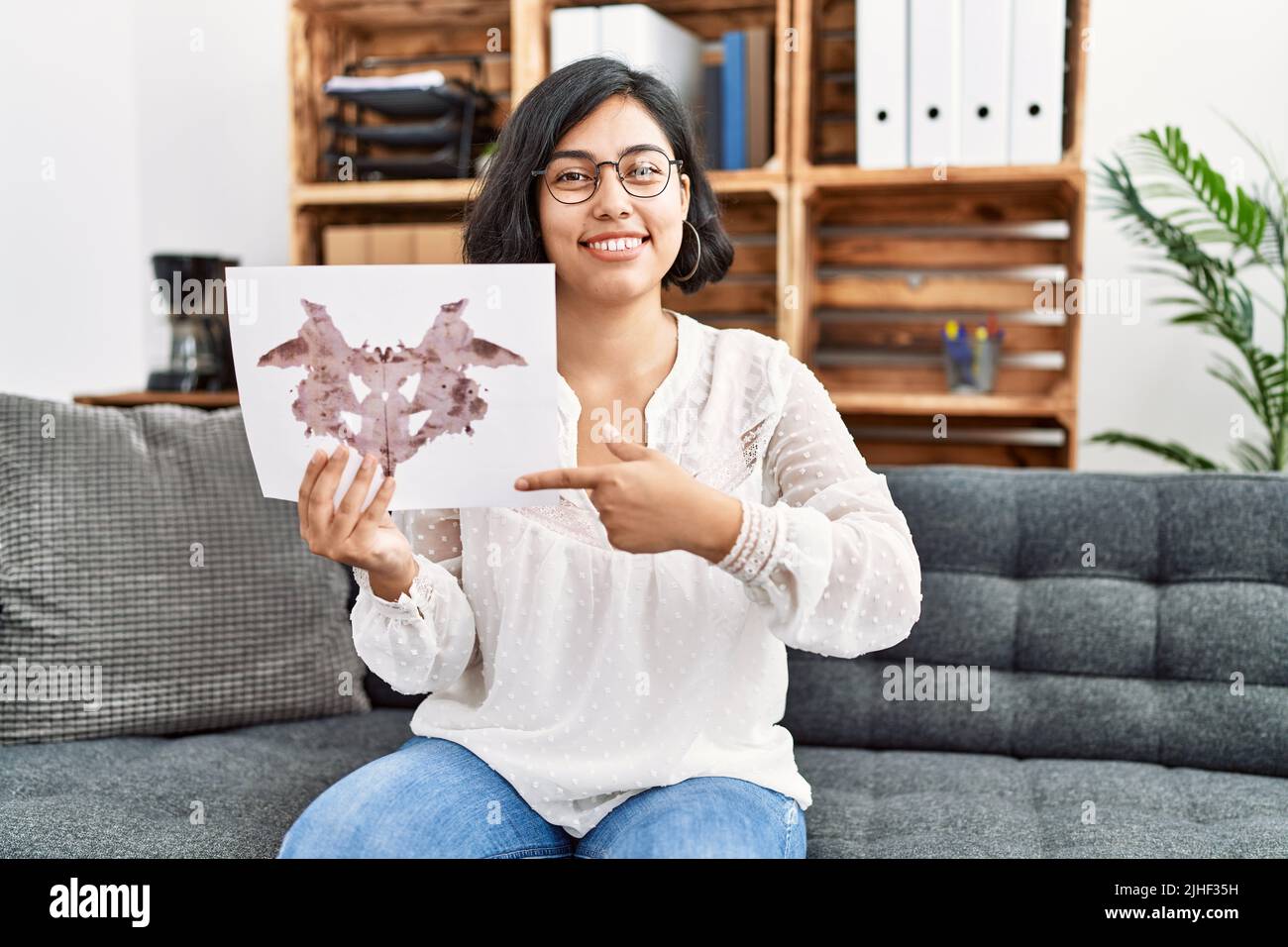 Young hispanic therapist woman holding rorschach test smiling happy ...