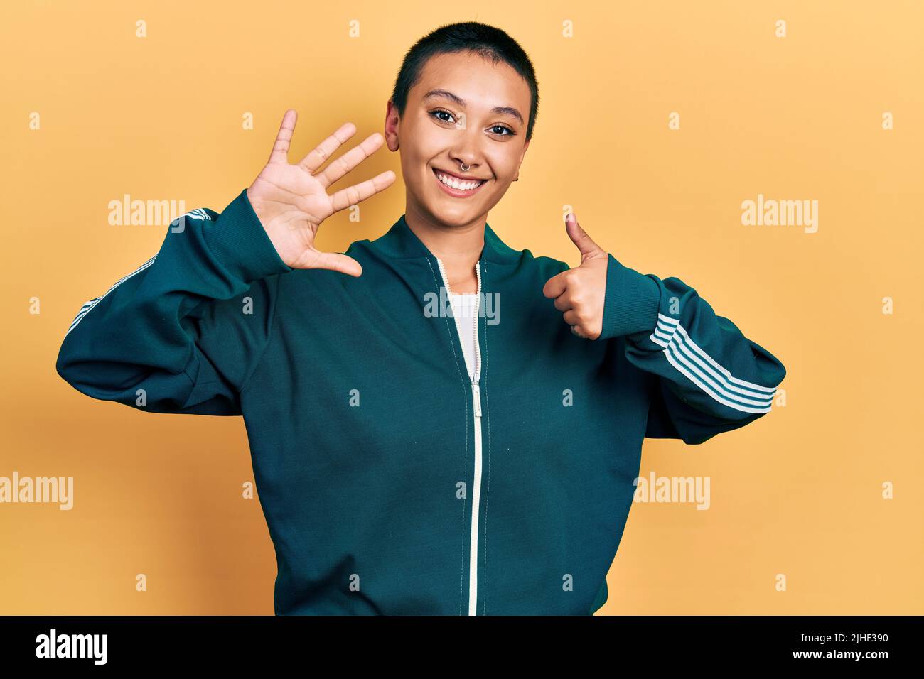 Beautiful hispanic woman with short hair wearing sporty jacket showing ...