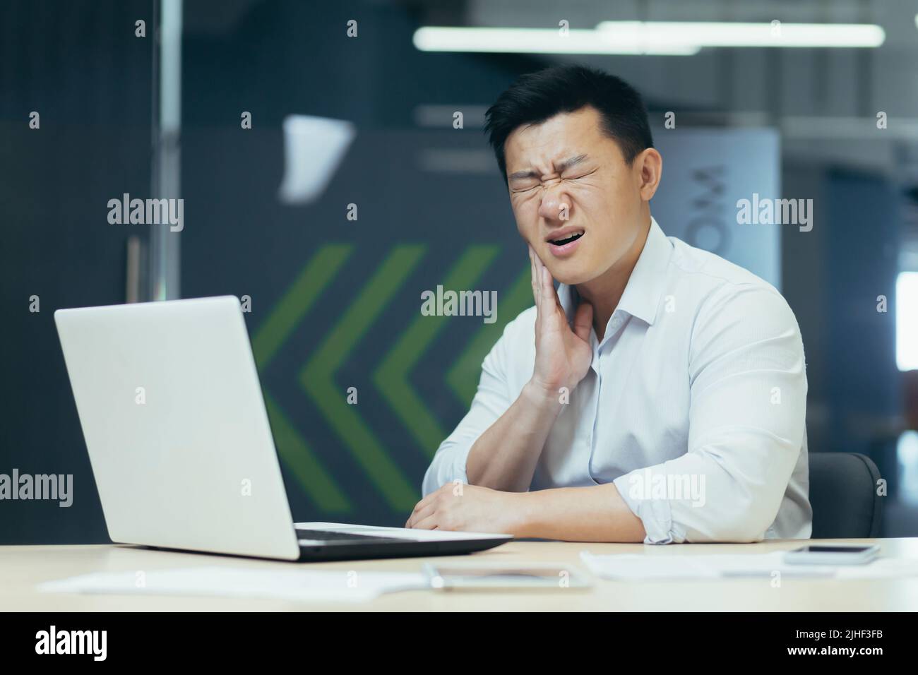 Asian man working in modern office, businessman having severe toothache ...
