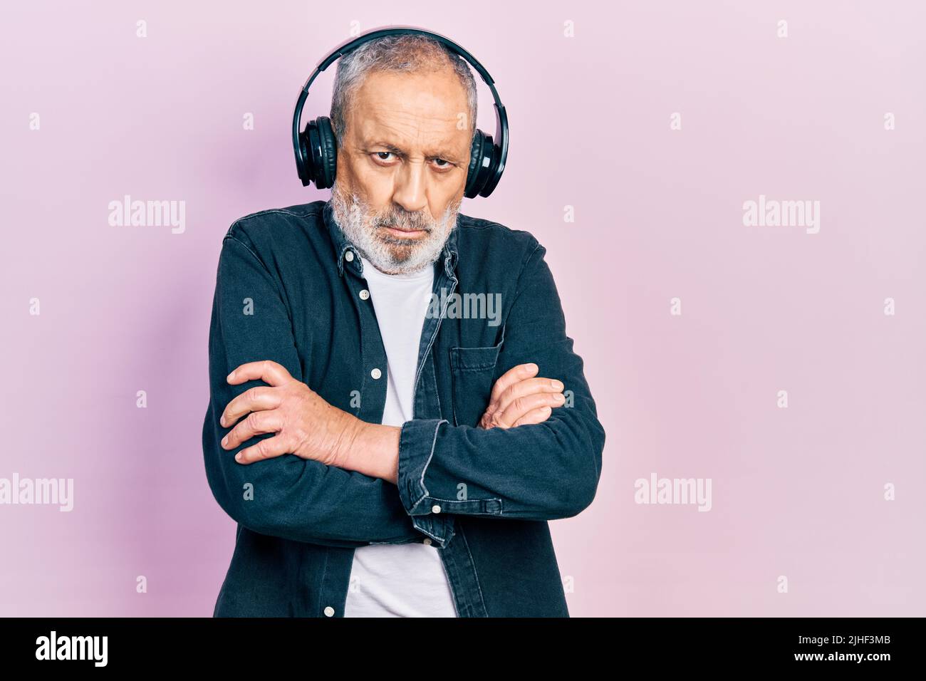 Handsome Senior Man With Beard Listening To Music Using Headphones