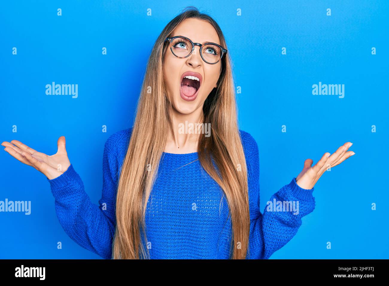 Young blonde girl wearing casual clothes and glasses crazy and mad ...