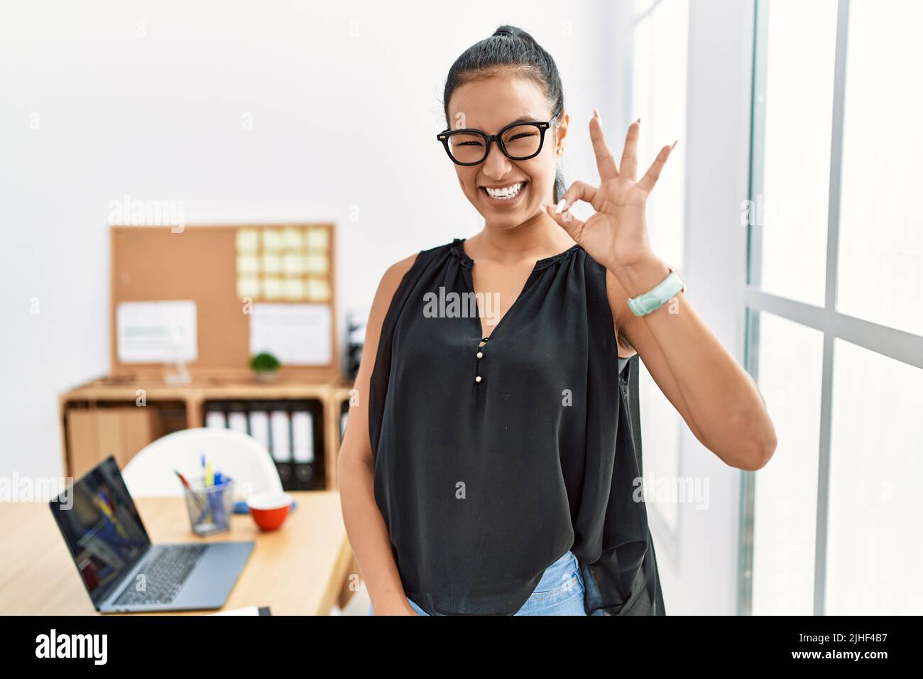 Young hispanic business woman working at the office smiling positive ...