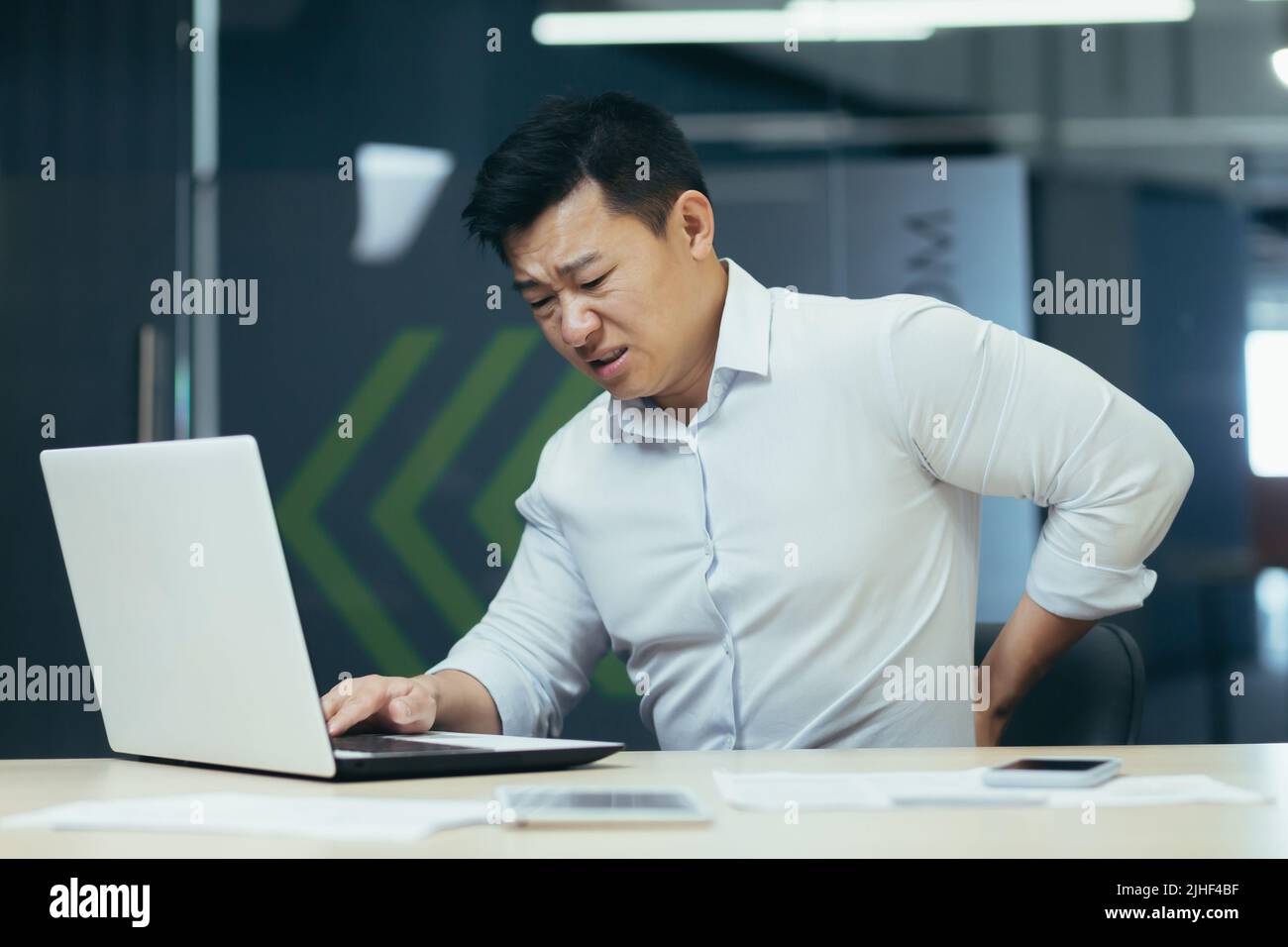 Asian businessman working in office, having severe back pain, overtired ...