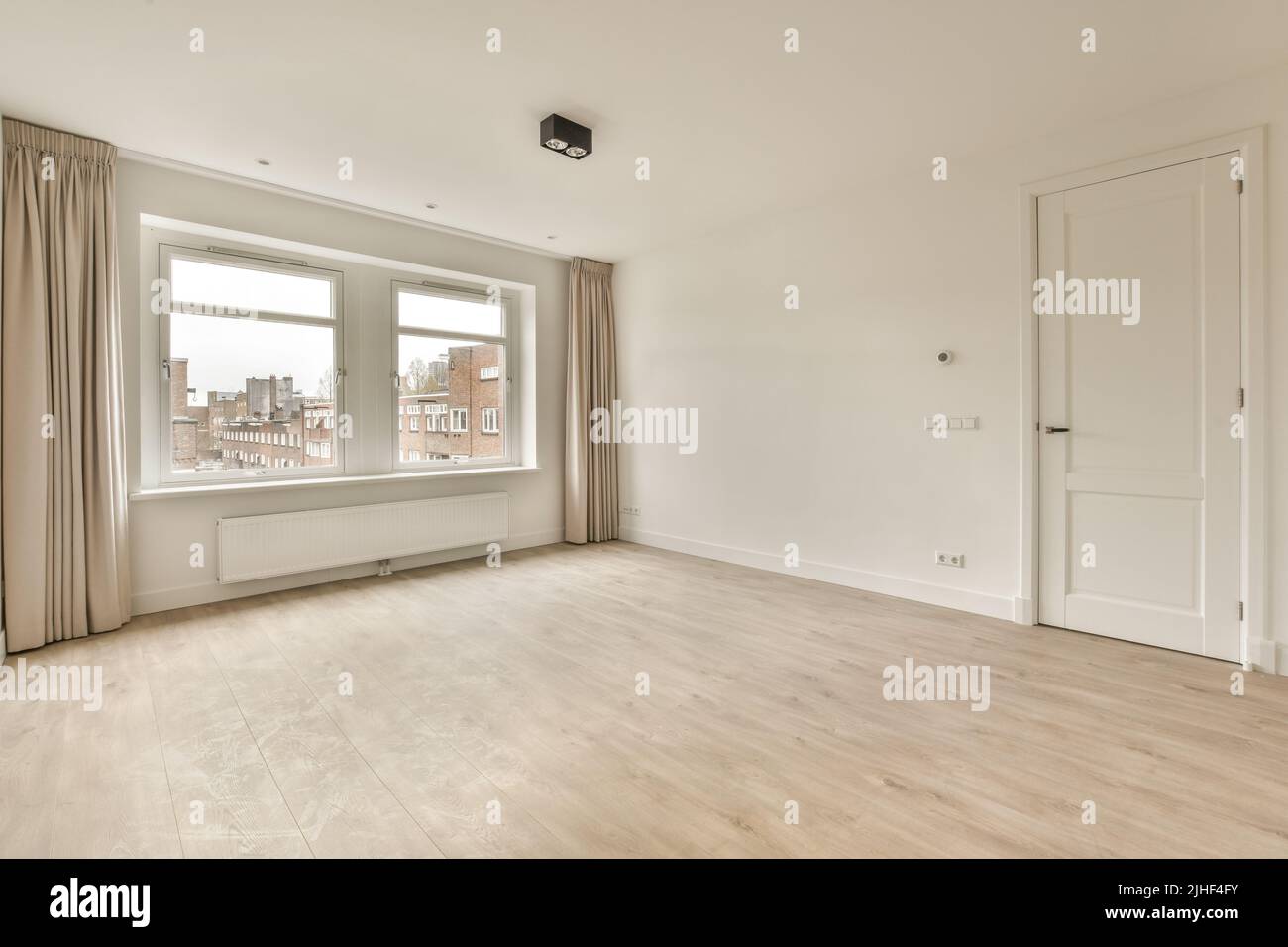 Plastic window and radiator on white wall in empty light room at home ...
