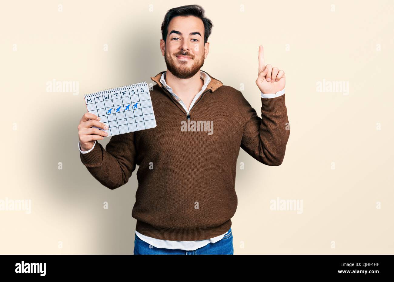 Young hispanic man holding travel calendar smiling with an idea or ...