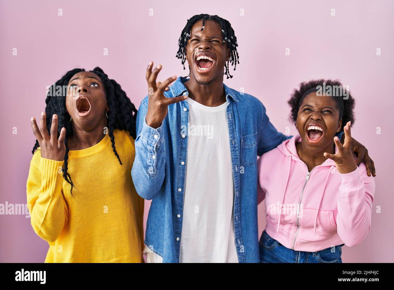 Group of three young black people standing together over pink ...
