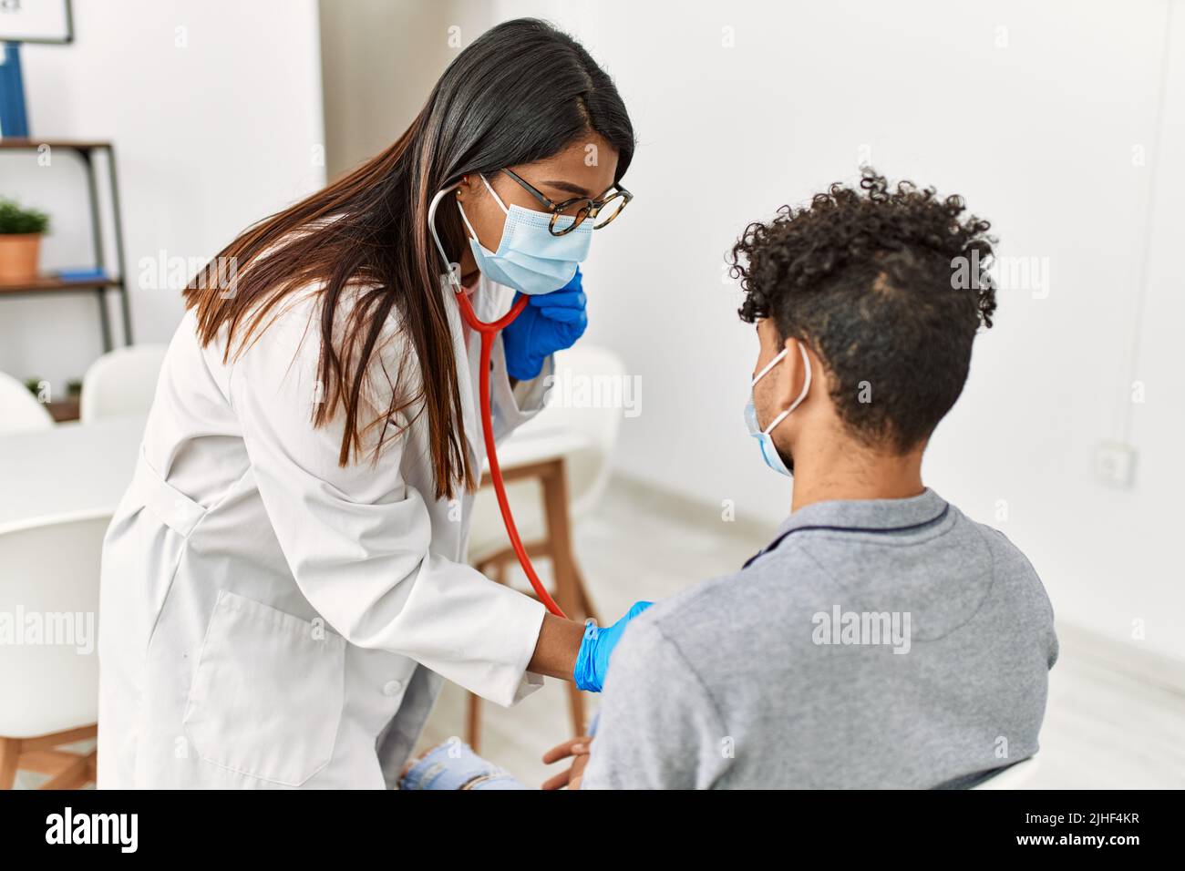 Young latin doctor woman auscultate heart man using stethoscope at ...