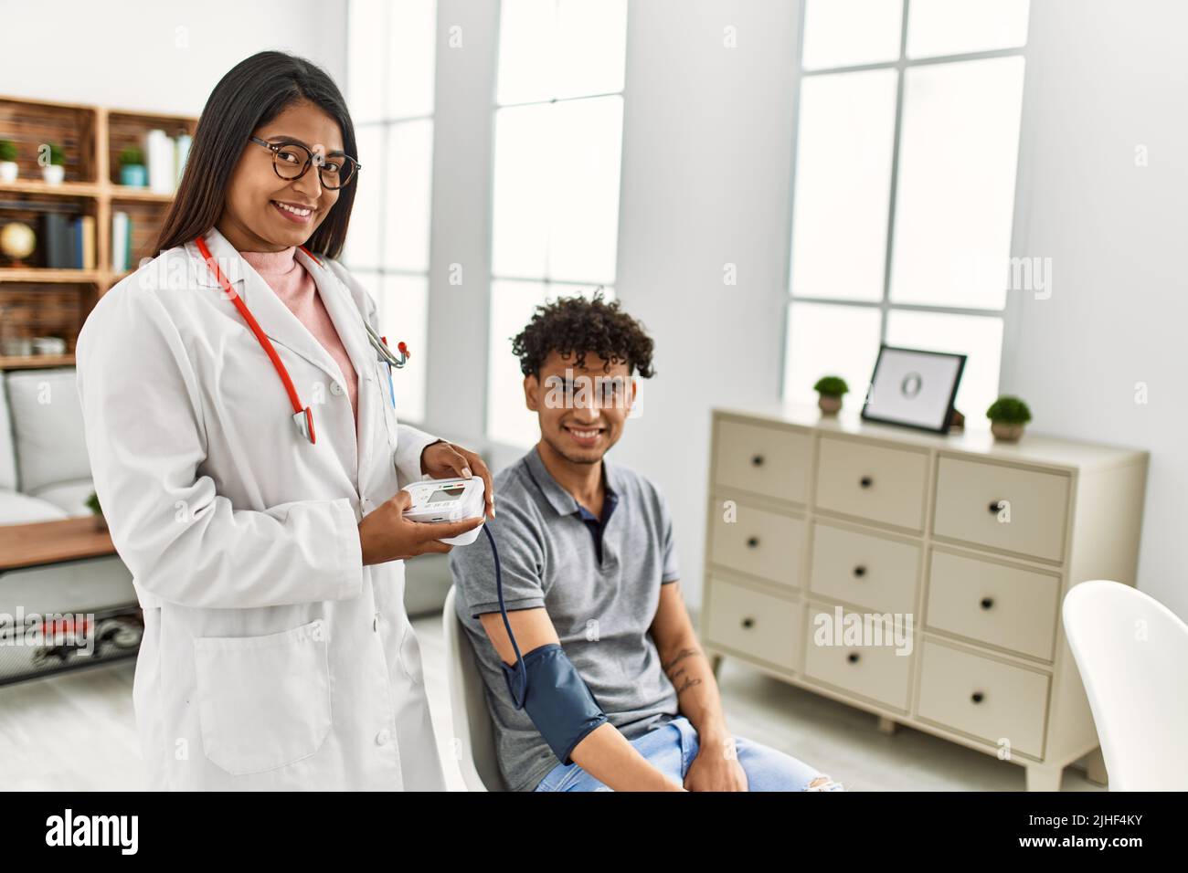 Young latin doctor woman smiling happy measuring pulse using ...