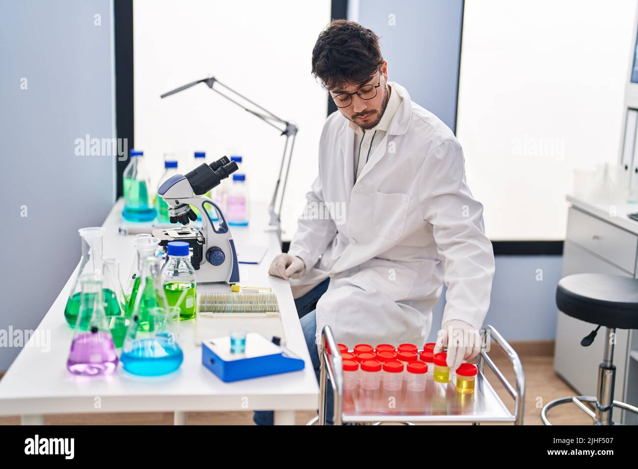 Young hispanic man scientist holding urine test tube at laboratory ...