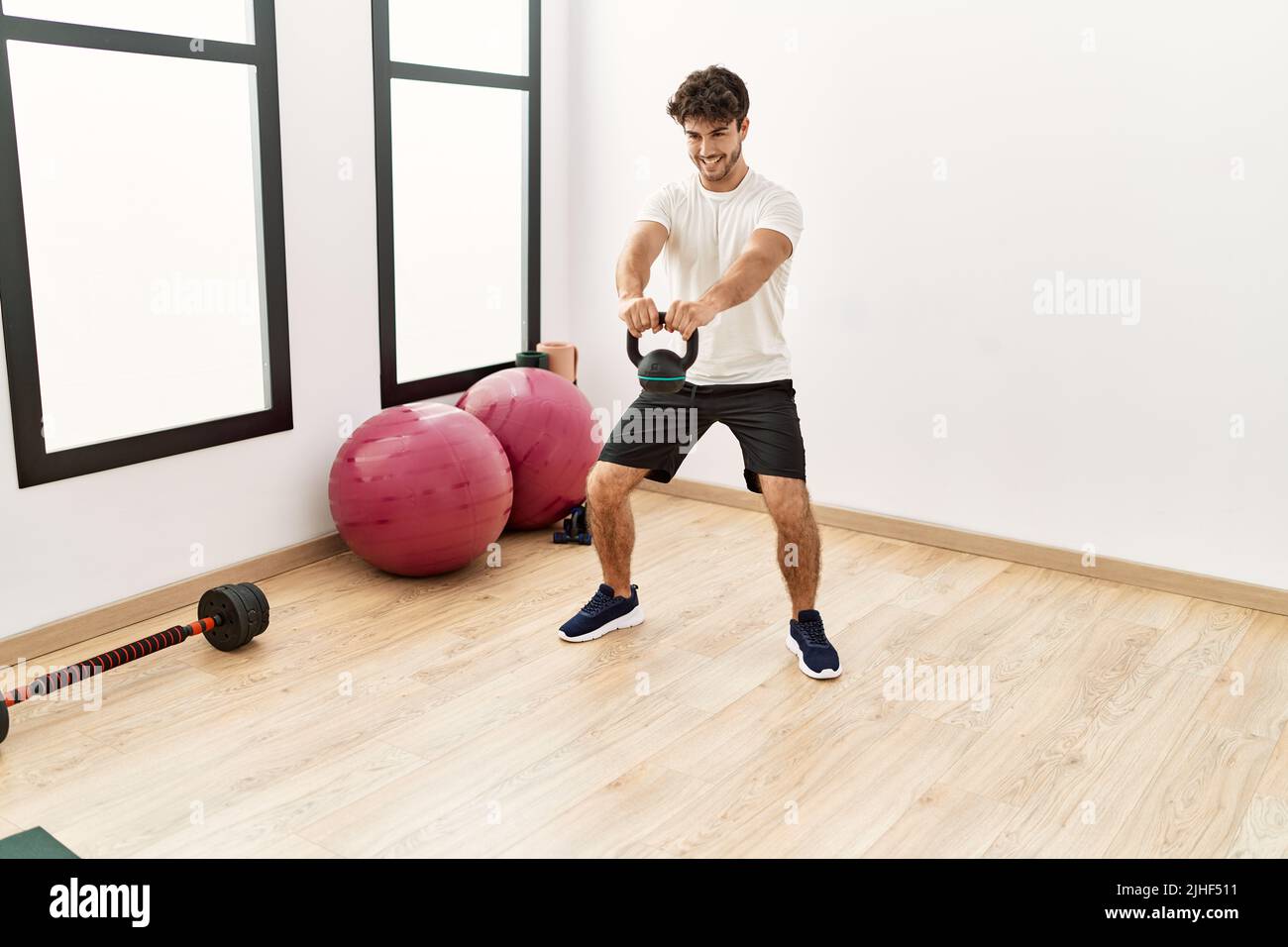 Young hispanic man smiling confident training with kettlebell at sport ...
