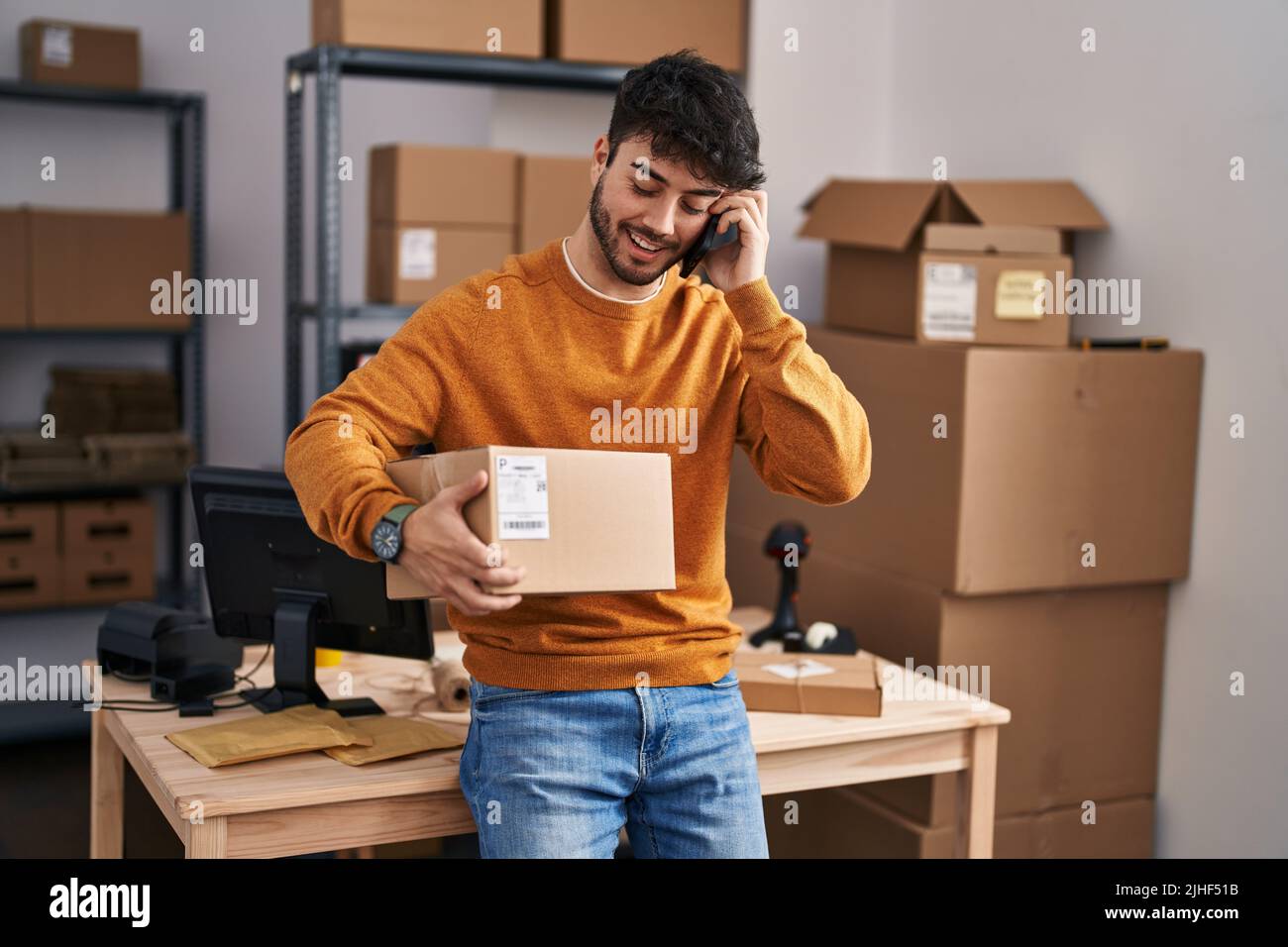 Young hispanic man ecommerce business worker talking on smartphone ...