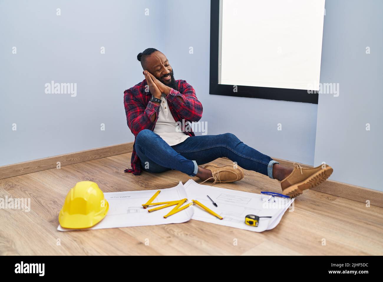 African american man sitting on the floor at new home looking at ...