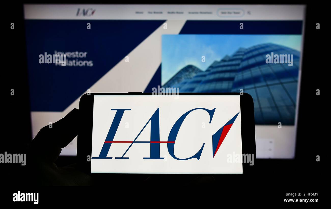 Person holding smartphone with logo of US media company IAC ...