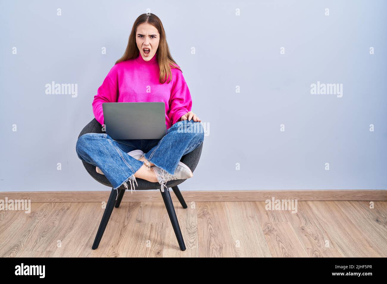 Young hispanic girl working using computer laptop angry and mad ...