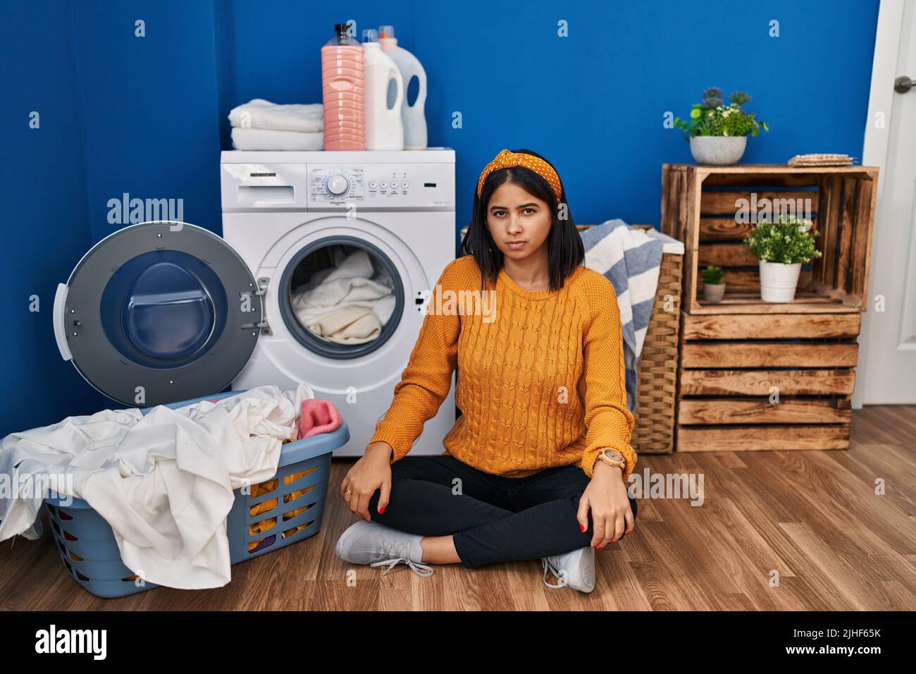 Young hispanic woman doing laundry skeptic and nervous, frowning upset ...