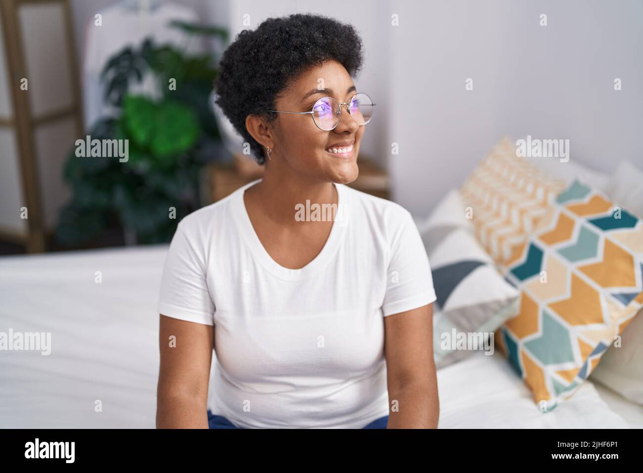 African american woman smiling confident sitting on bed at bedroom ...
