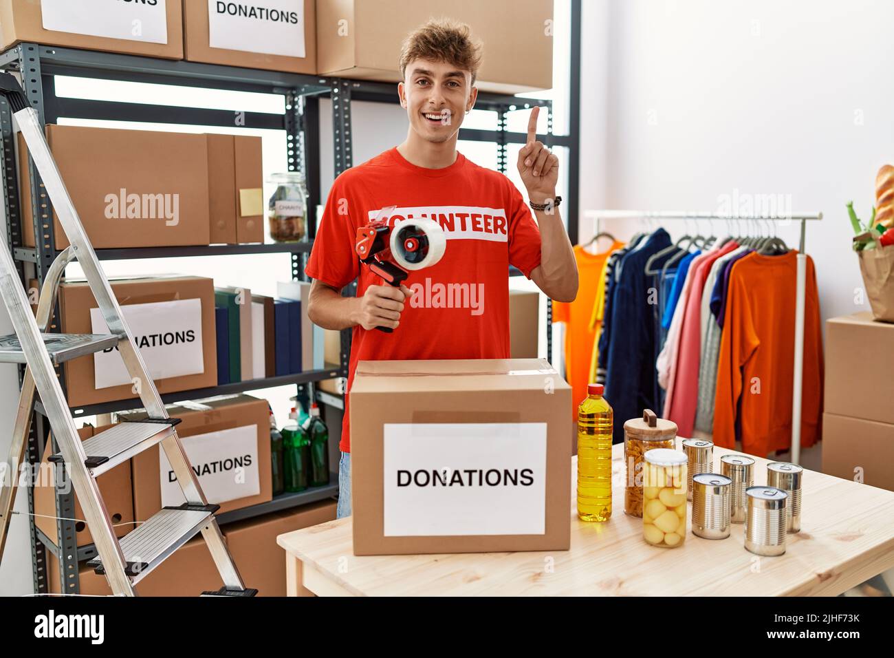 Young caucasian volunteer man packing donations box at charity center ...