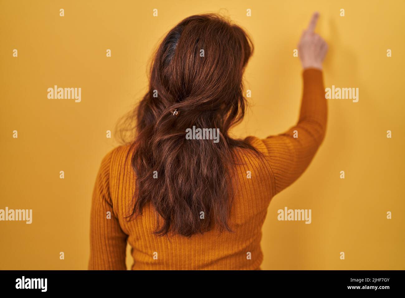 Middle age hispanic woman standing over yellow background posing ...