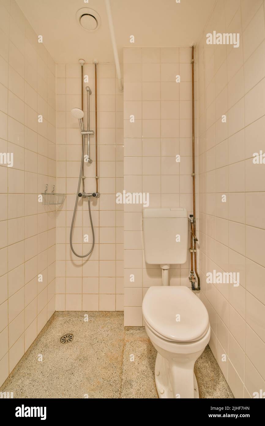 Wall hung toilet and shower box in corner in room with beige tile Stock ...