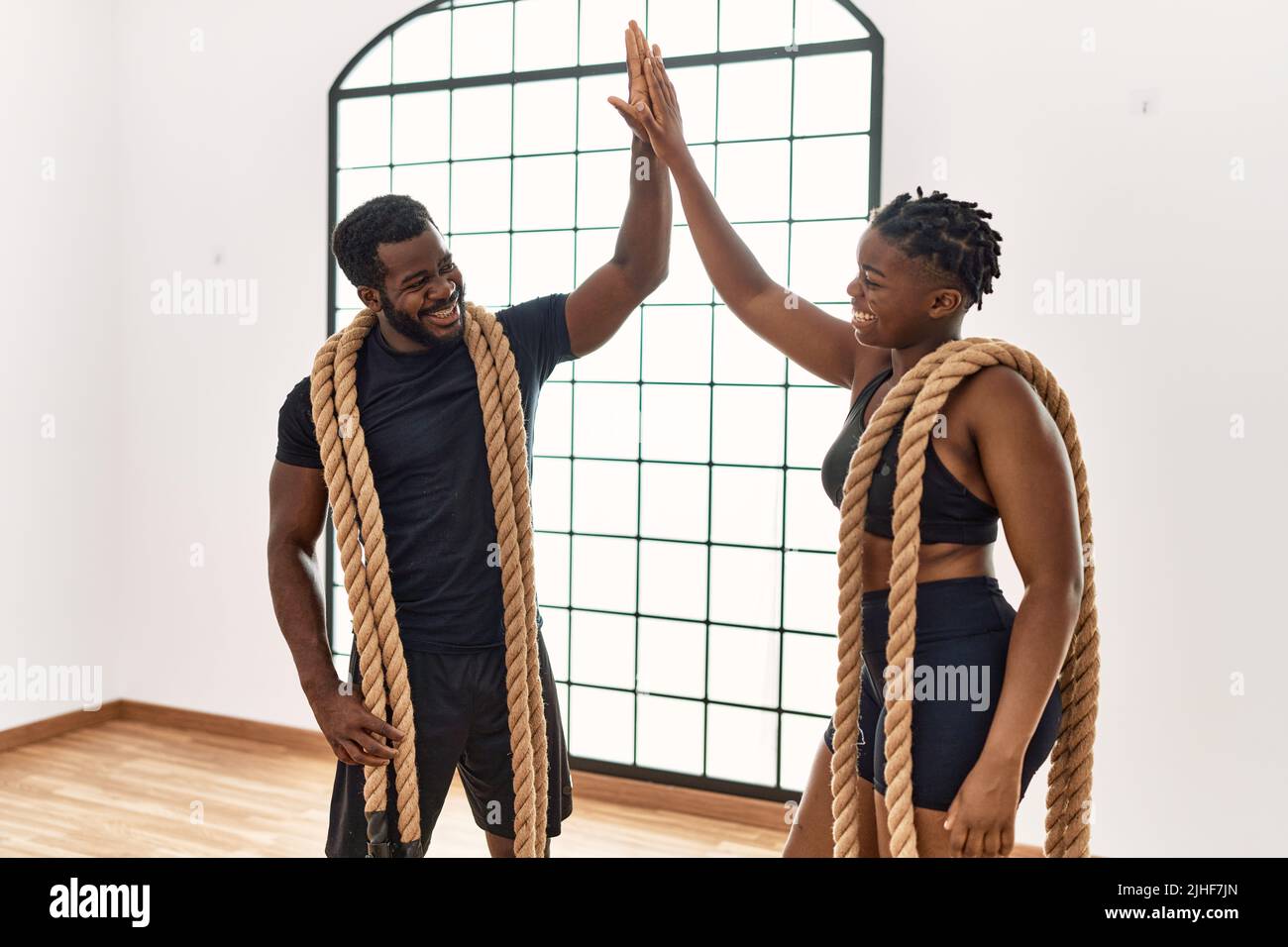 Young african american sporty couple smiling happy holding battle rope ...