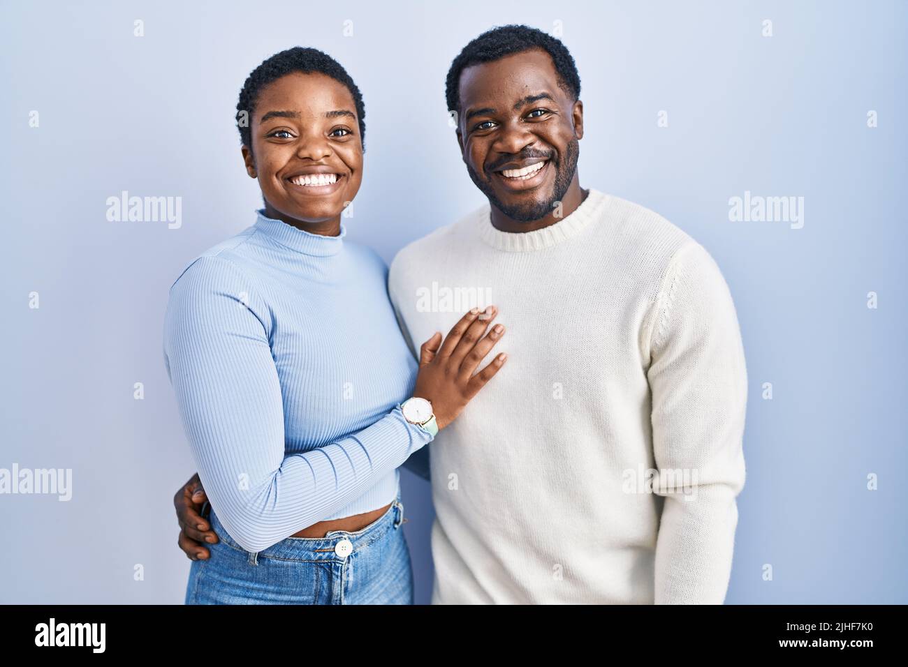 Young african american couple standing over blue background with a ...