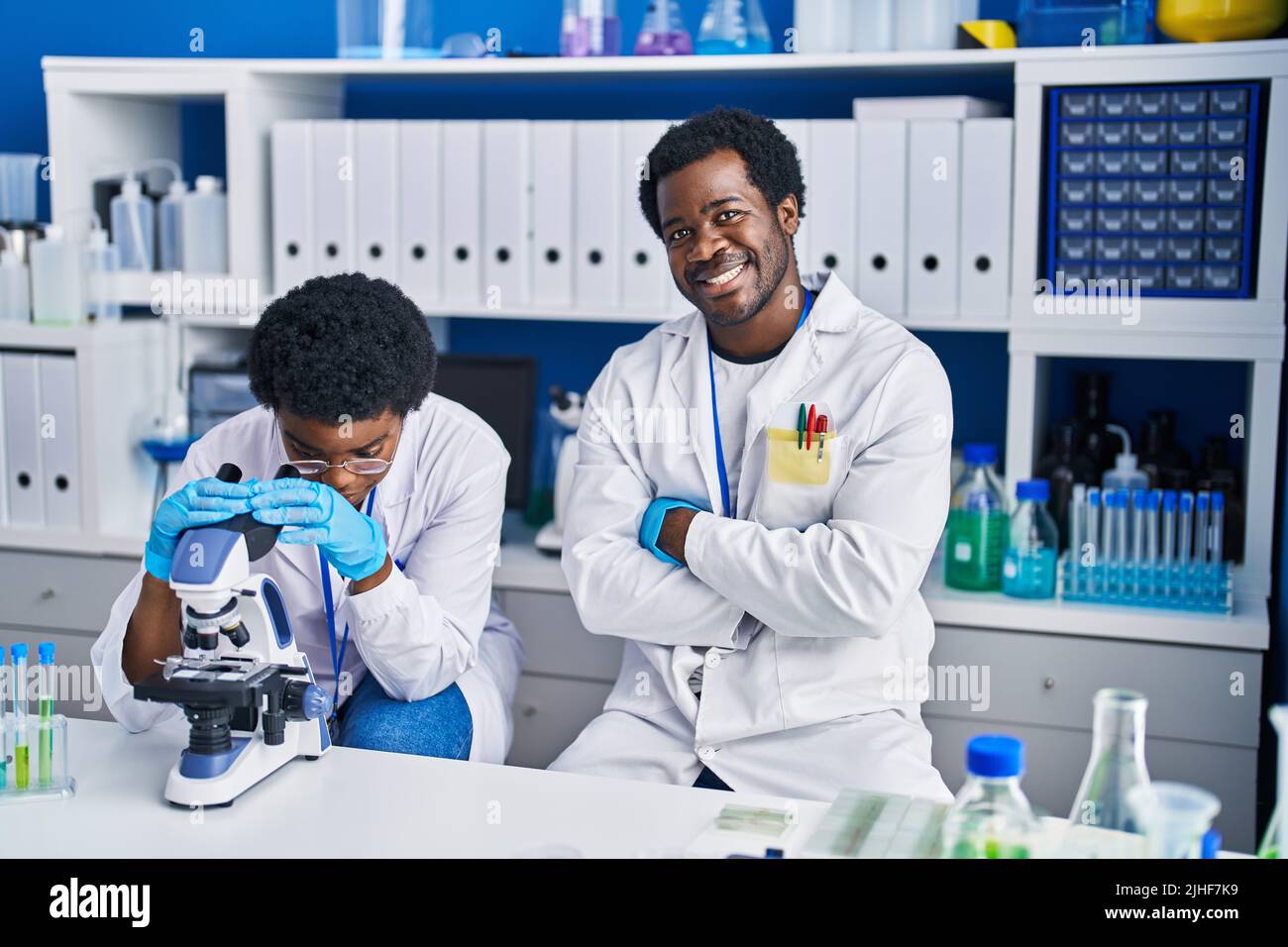 African american man and woman scientists using microscope at laboratory Stock Photo - Alamy
