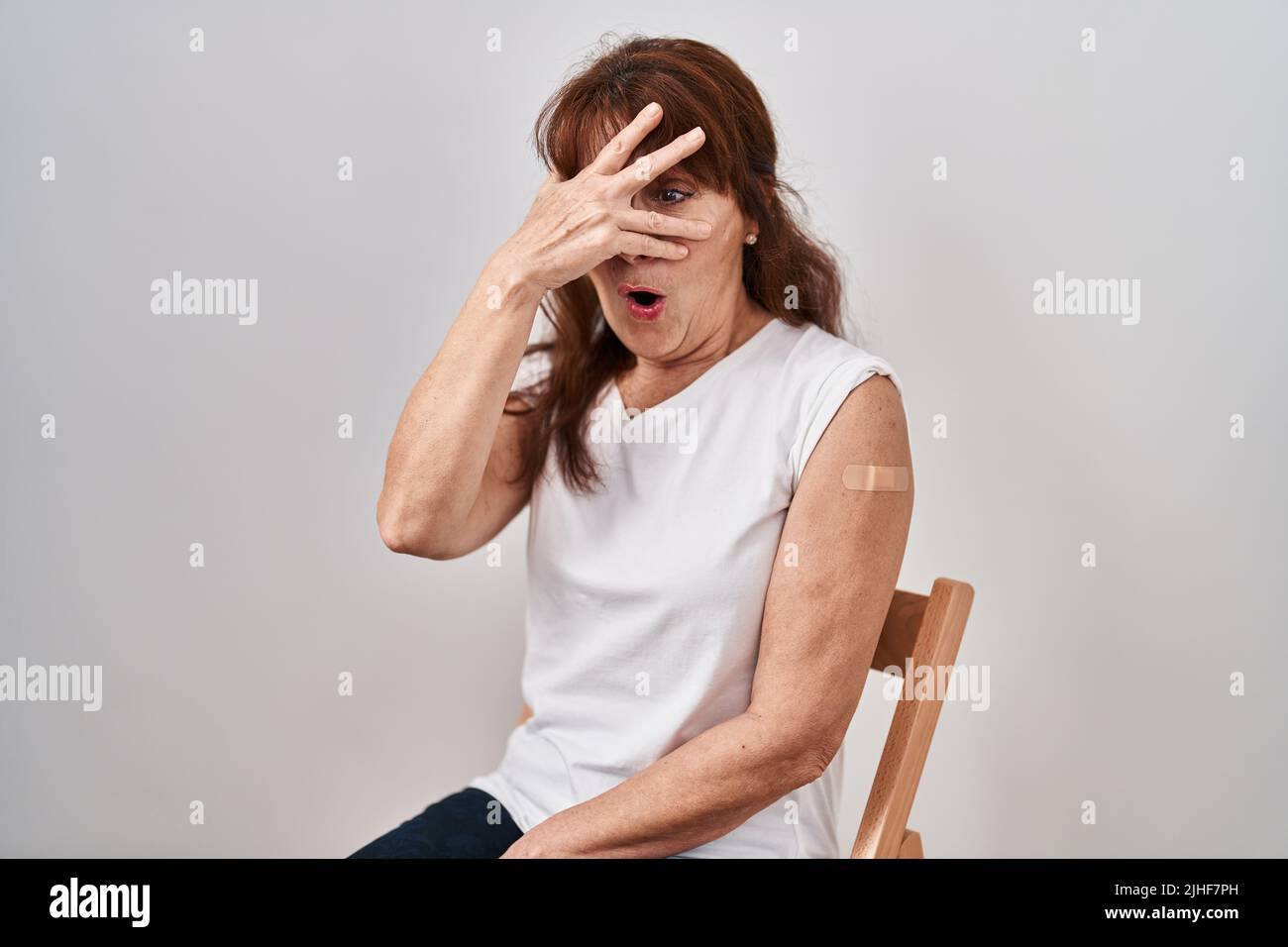 Middle age hispanic woman getting vaccine showing arm with band aid ...