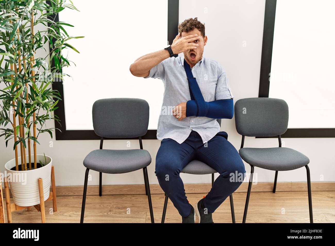 Handsome young man sitting at doctor waiting room with arm injury ...