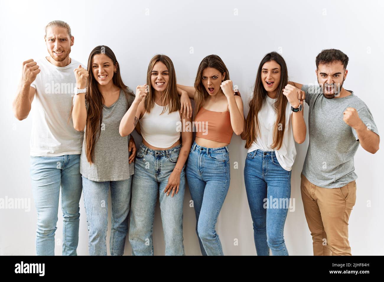 Group of young friends standing together over isolated background angry ...