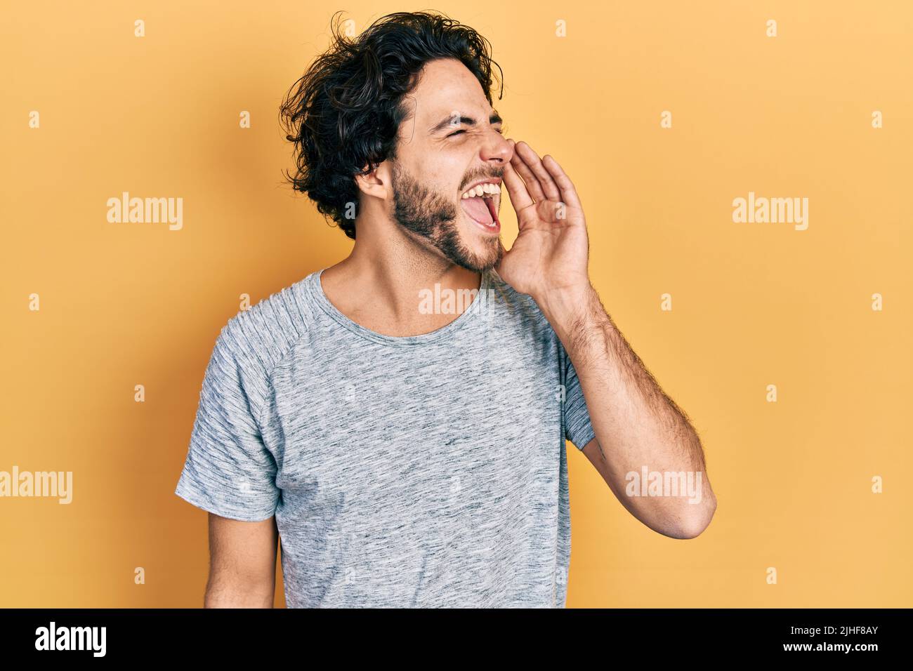 Handsome hispanic man wearing casual grey t shirt shouting and ...