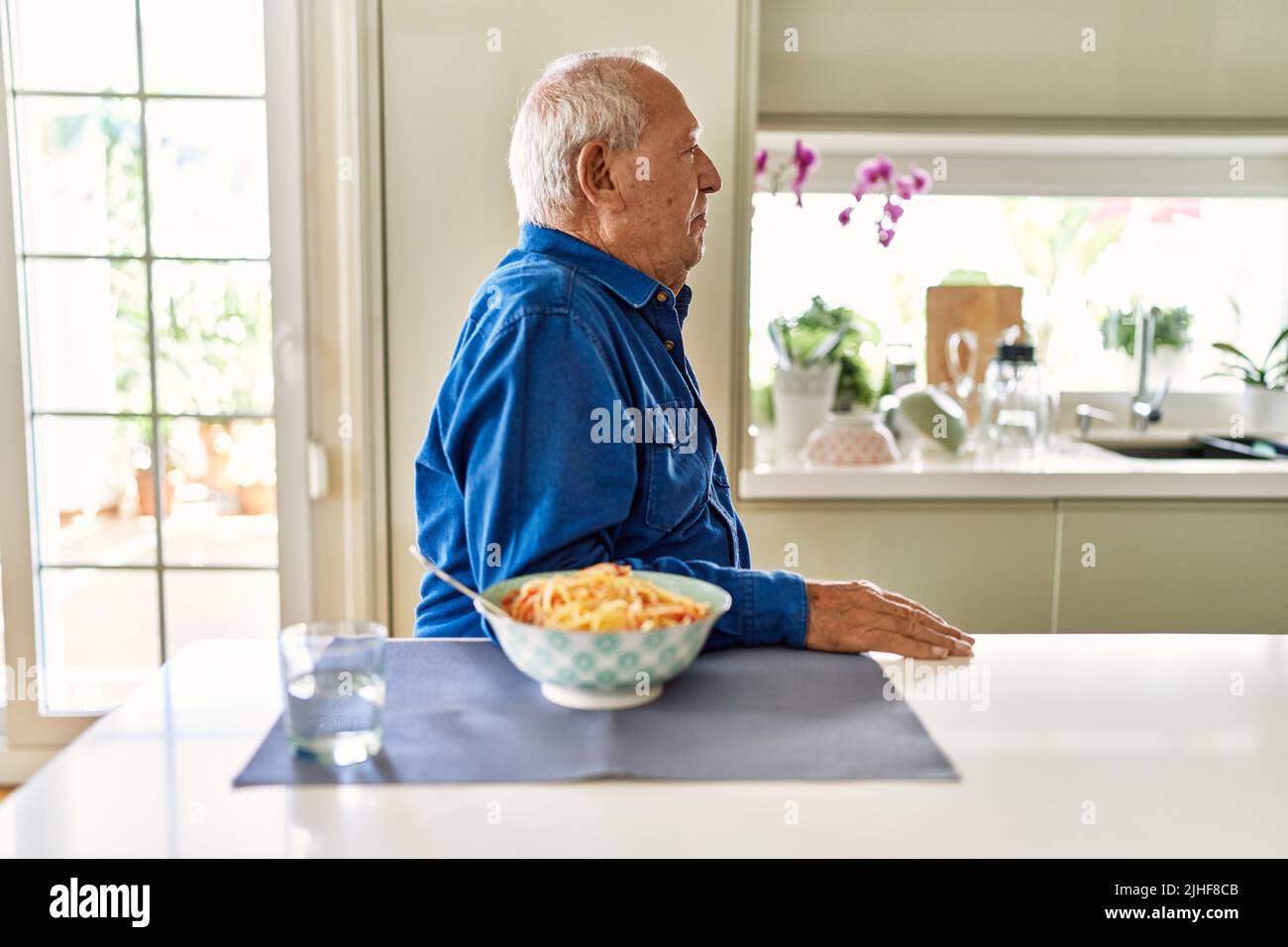 Senior man with grey hair eating pasta spaghetti at home looking to ...