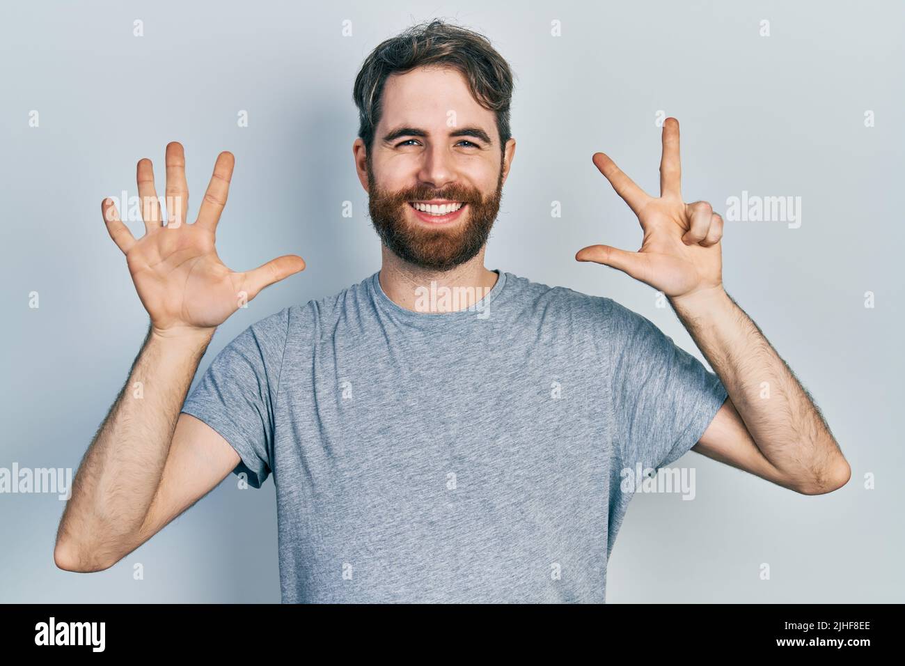Caucasian man with beard wearing casual grey t shirt showing and ...