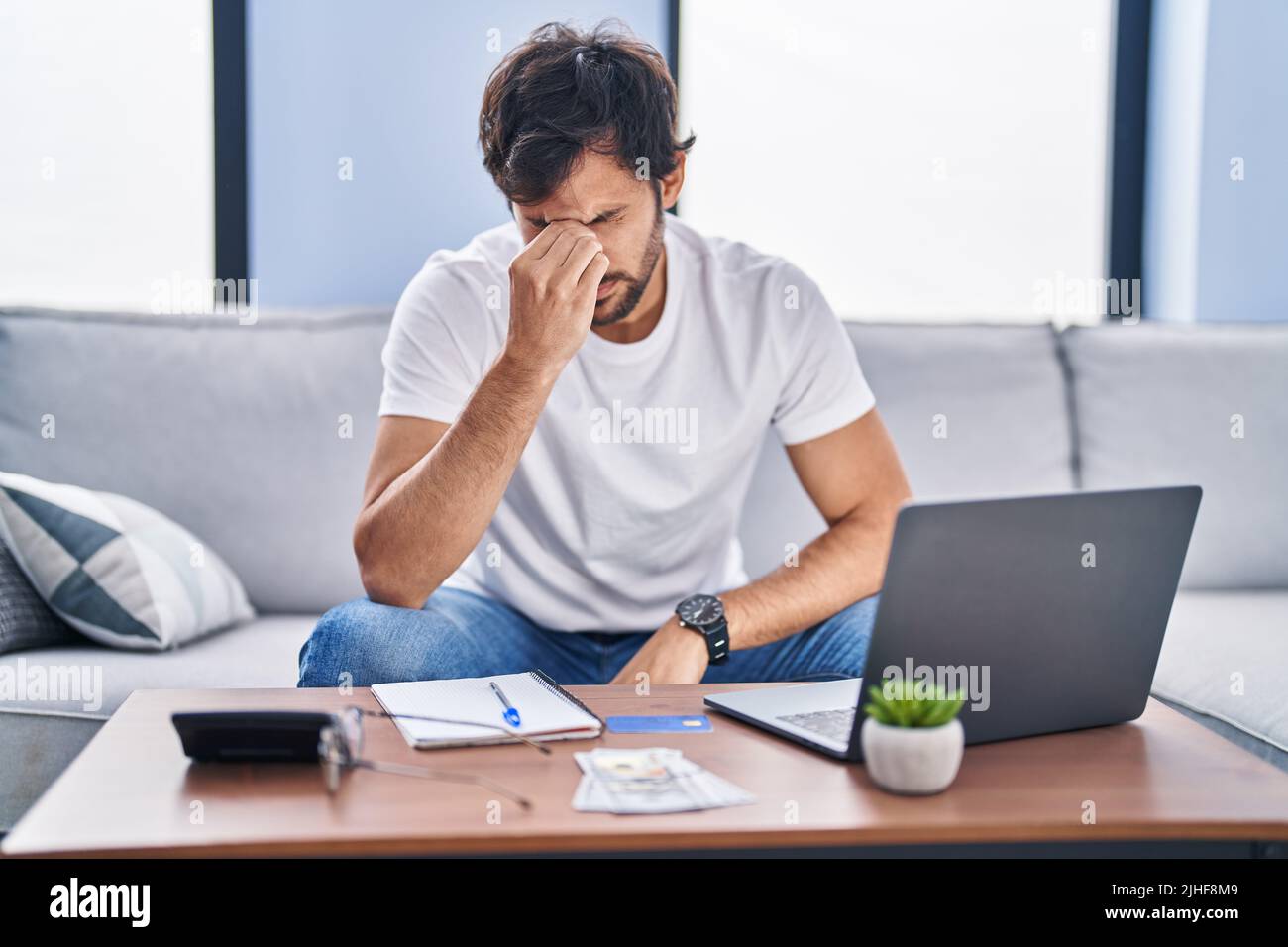 Young hispanic man stressed using laptop working at home Stock Photo ...