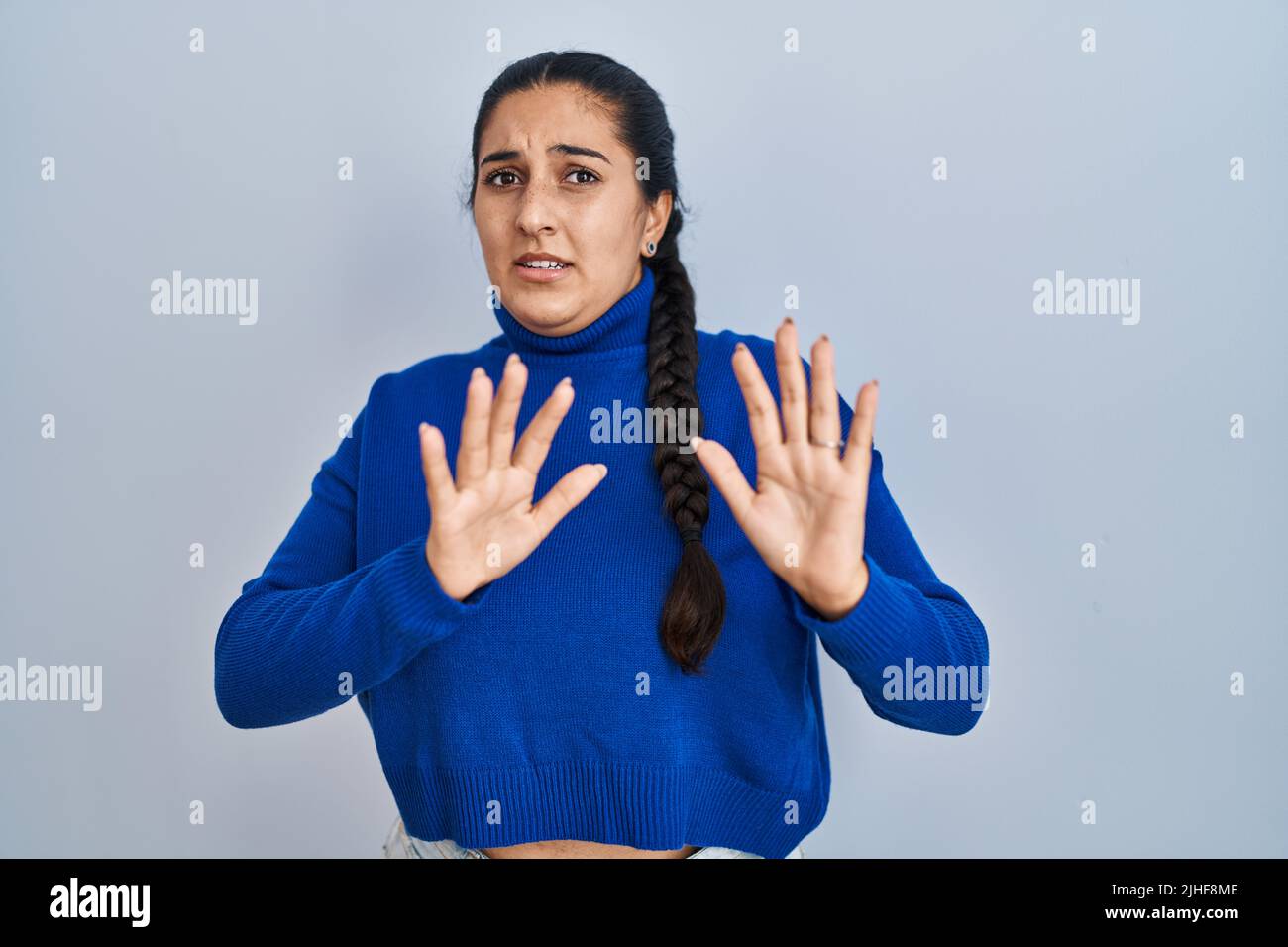 Young hispanic woman standing over isolated background afraid and ...