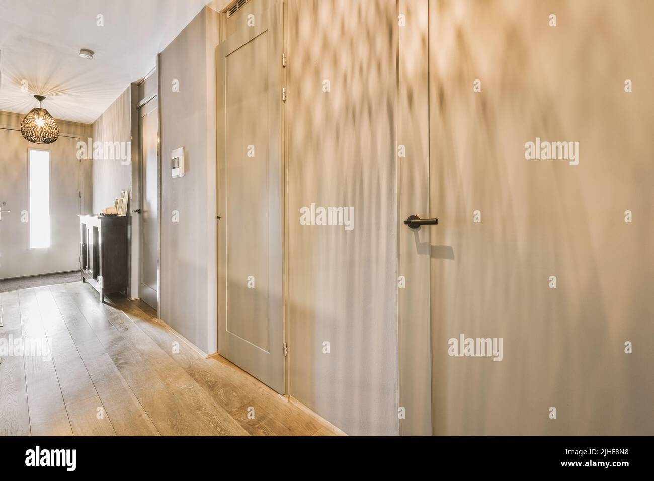 Light narrow hallway with many doors in white walls and glowing lamp ...