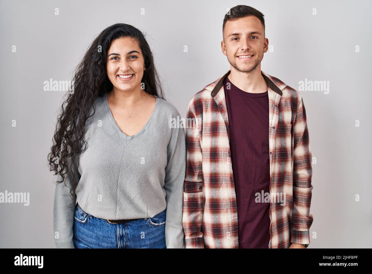 Young hispanic couple standing over white background with a happy and ...
