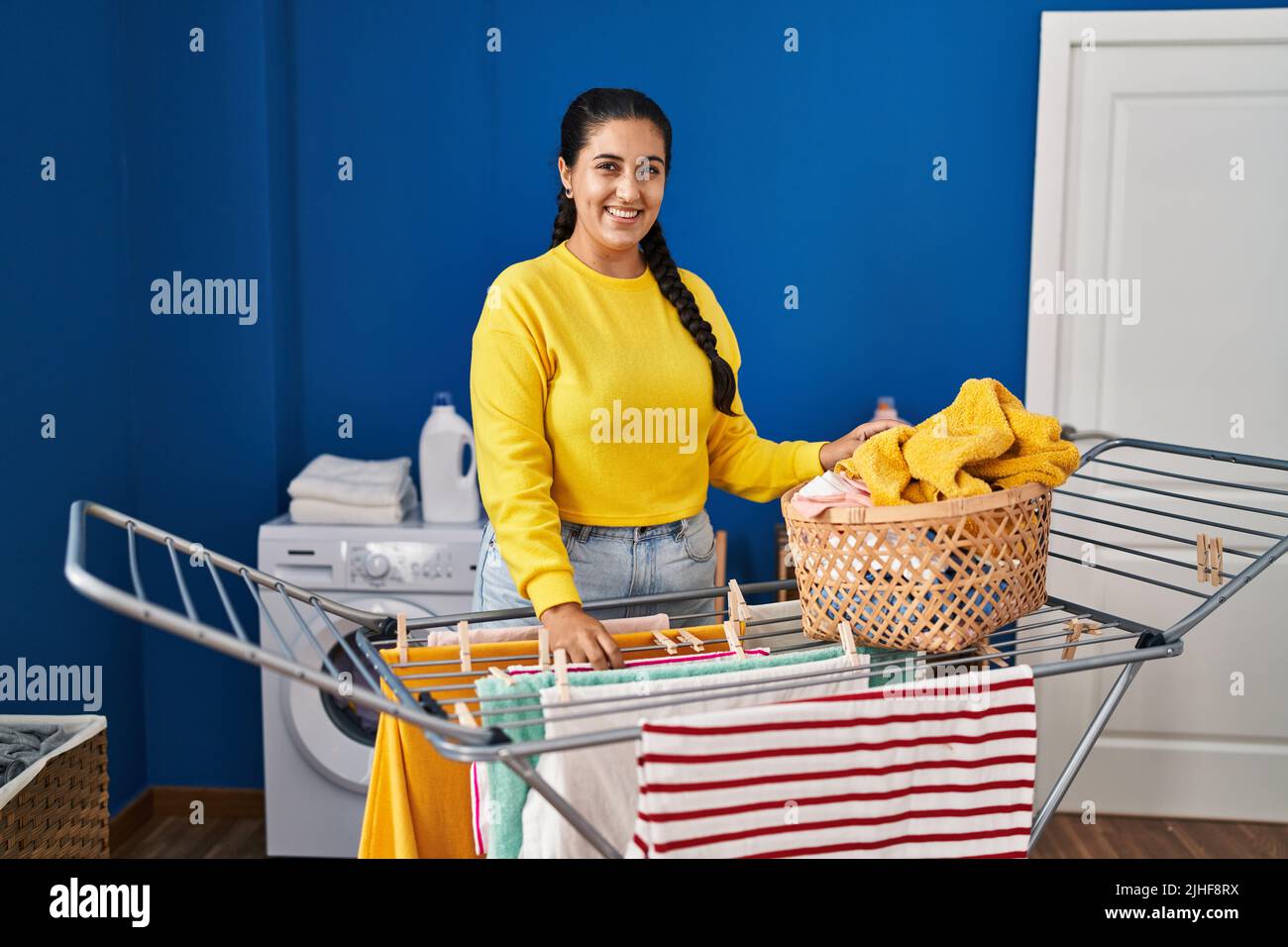 Young hispanic woman smiling confident hanging clothes on clothesline ...