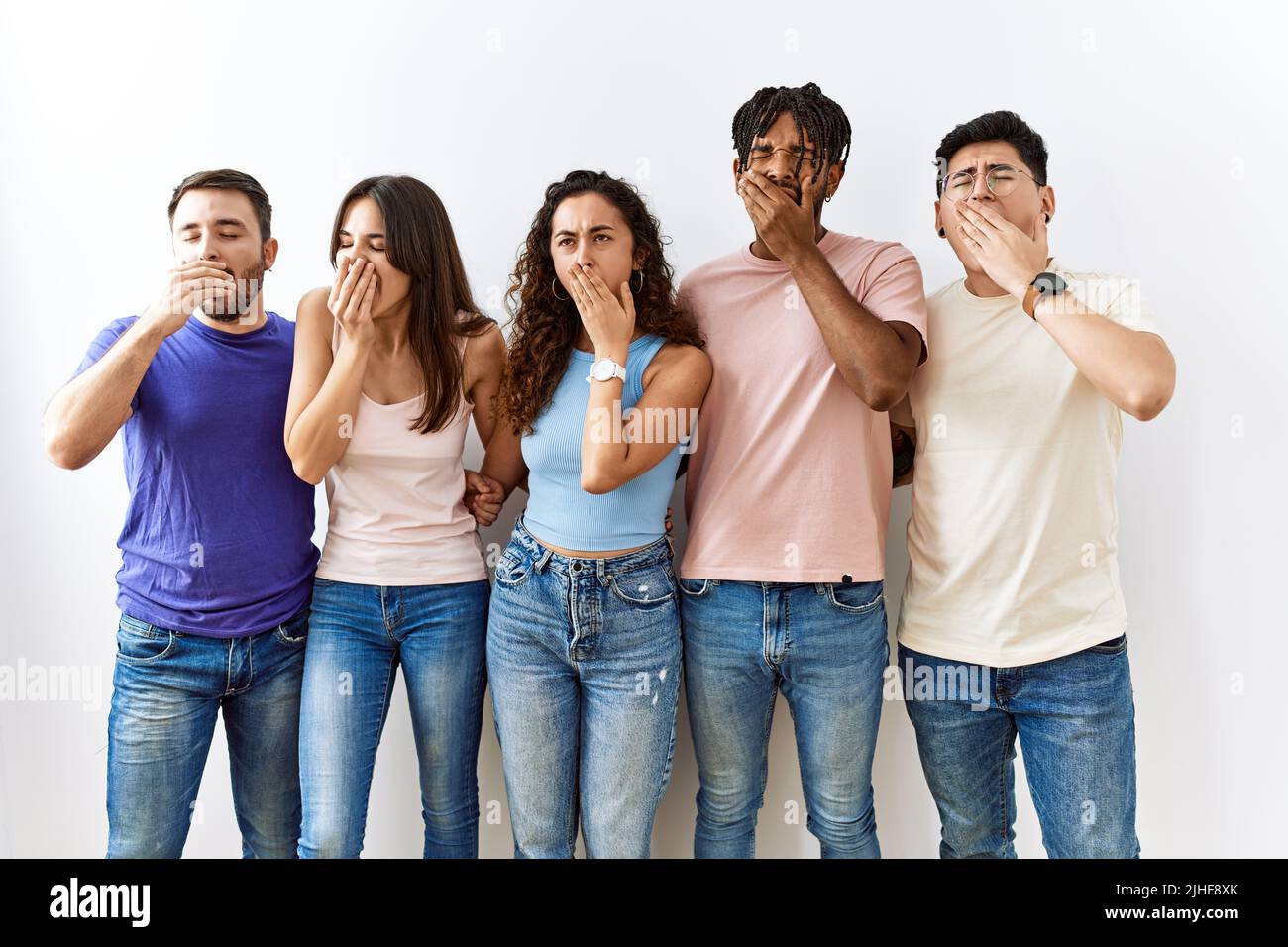 Group of young people standing together over isolated background bored ...
