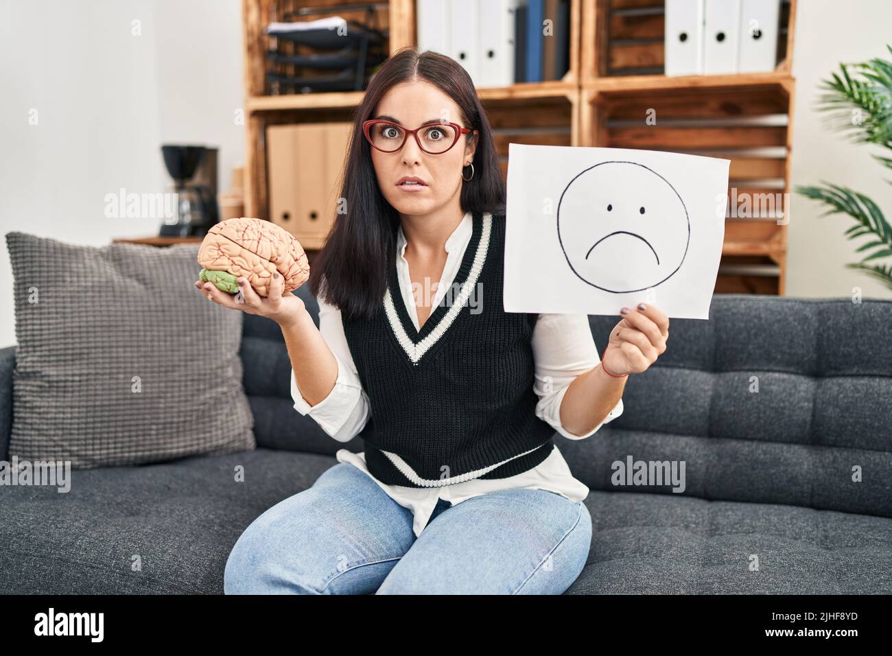 Young hispanic woman working on depression holding sad emotion paper ...