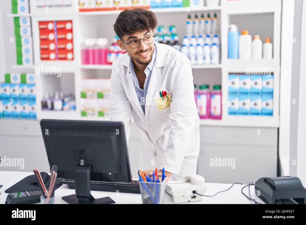 Young arab man pharmacist using computer working at pharmacy Stock ...