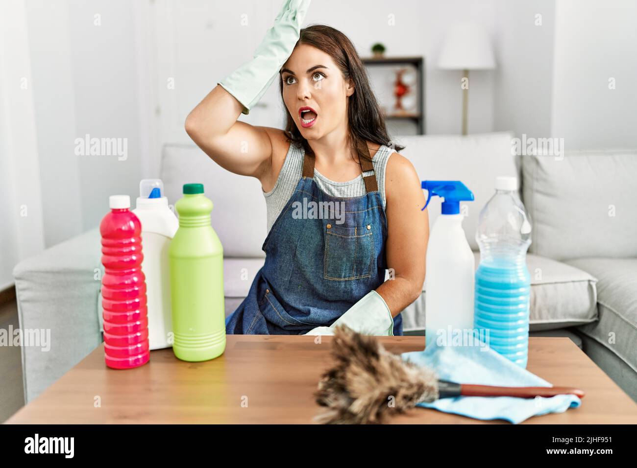 Young brunette woman wearing cleaner apron and gloves cleaning at home ...