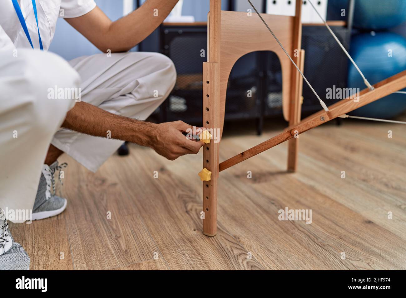 Young hispanic man wearing physiotherapist uniform manipulating massage ...