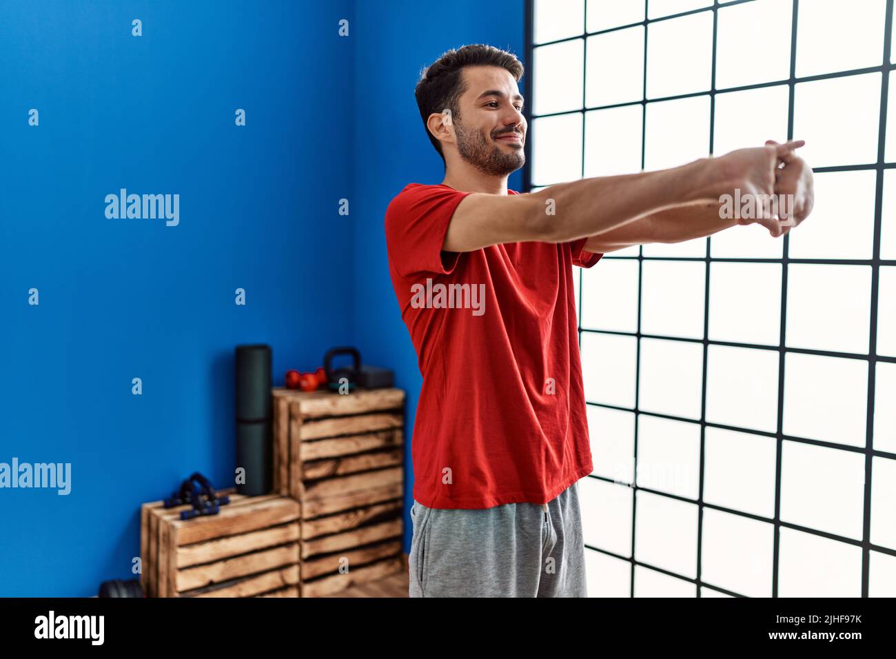 Young hispanic man smiling confident stretching at sport center Stock ...