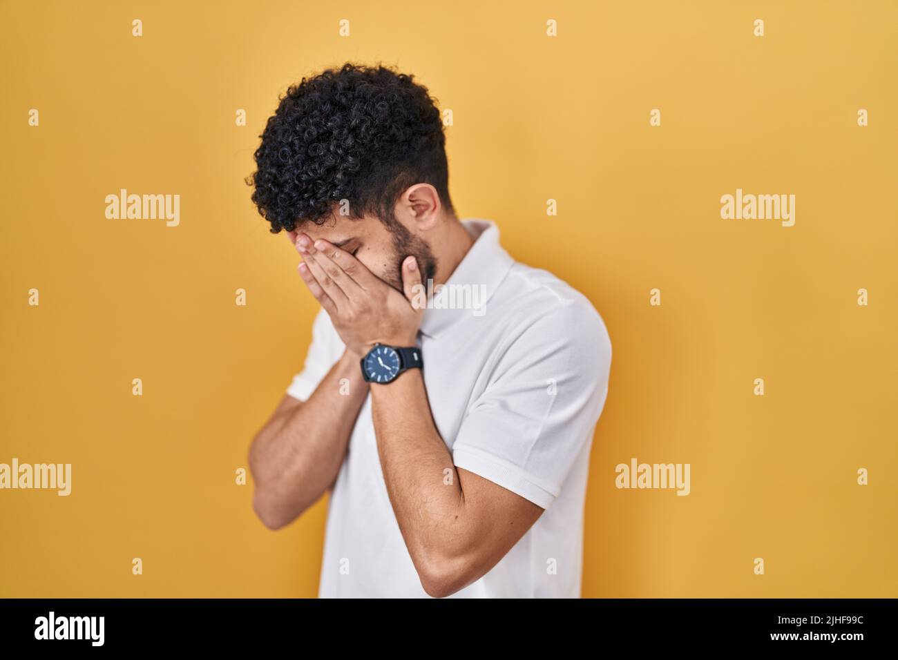 Arab man standing over yellow background with sad expression covering ...