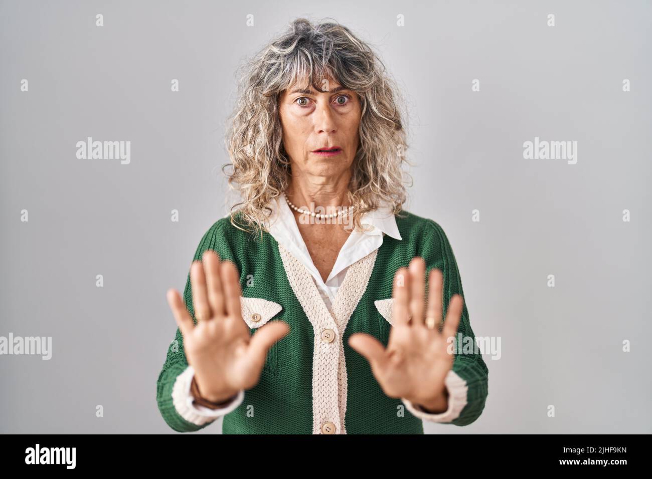 Middle age woman standing over white background moving away hands palms ...