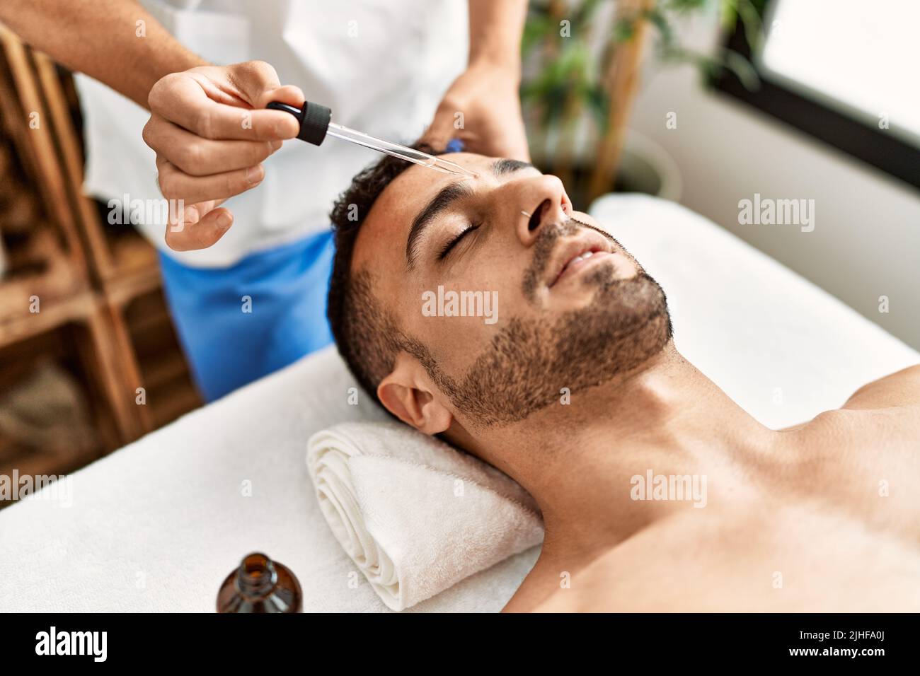 Two hispanic men therapist and patient having facial treatment using ...
